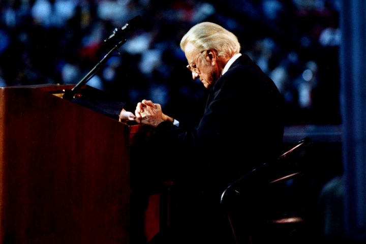 Billy Graham praying at St. Louis crusade 1999 - The Billy Graham Library